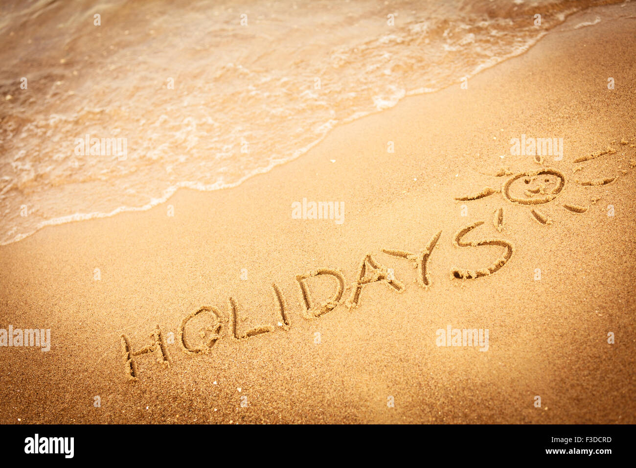 Summer vacation concept. The word holidays written in the sand on beach ...