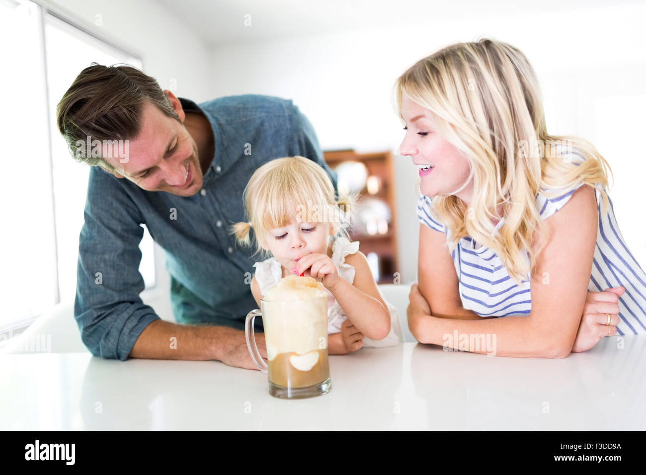 Girl (2-3) drinking milkshake with parents at home Stock Photo - Alamy