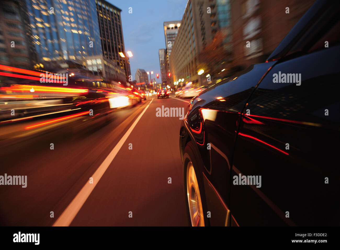 Car driving through city at dusk Stock Photo - Alamy