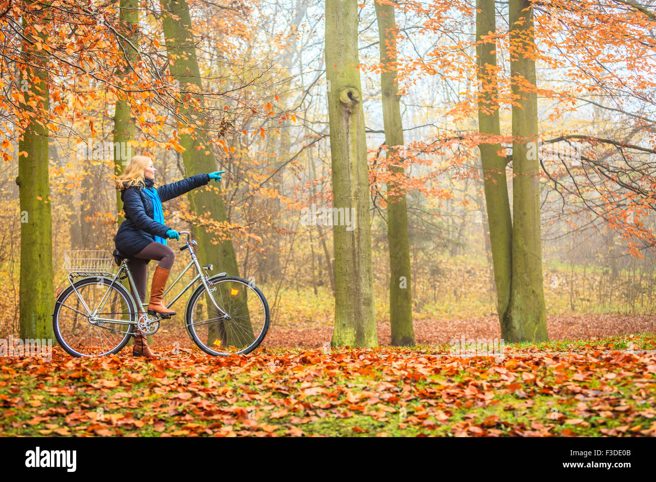 Active woman riding bike bicycle in fall autumn park. Young girl in ...