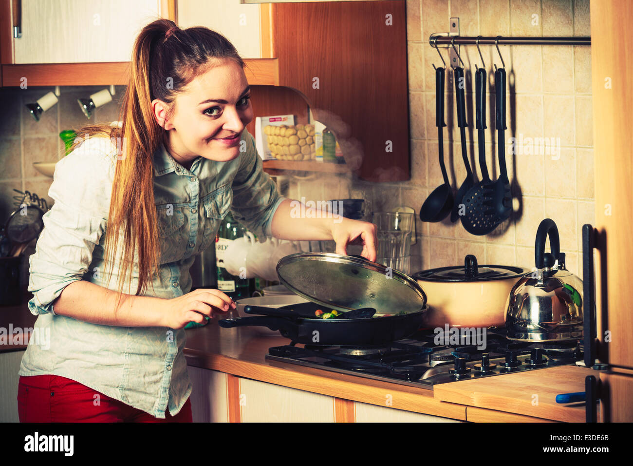 Woman in kitchen cooking stir fry frozen vegetables. Girl frying making ...