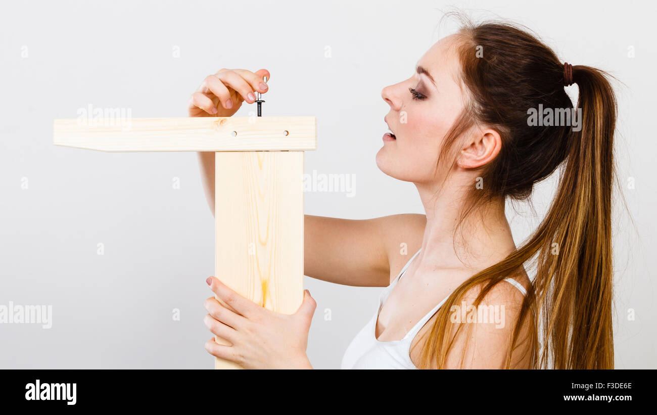 Woman assembling wooden furniture using hex key. DIY enthusiast. Young ...