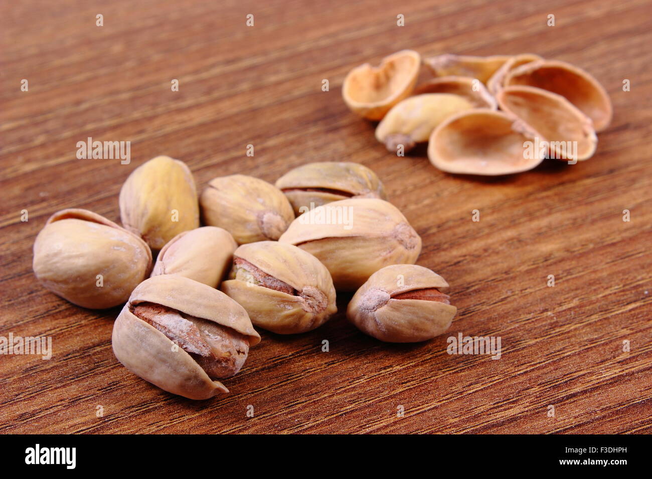Roasted pistachio nuts with shells on natural wooden table background, healthy food and ...