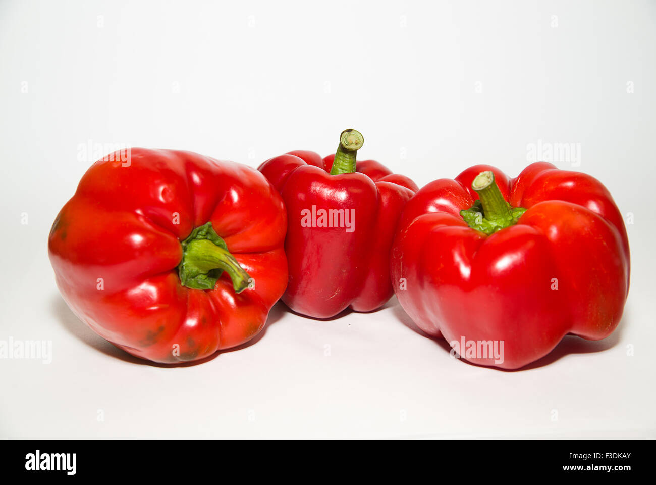 Three red peppers on a white background Stock Photo - Alamy