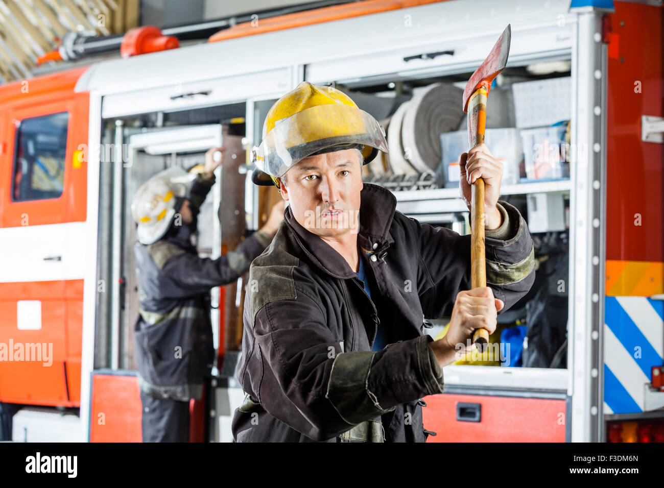 Confident Fireman Holding Axe At Fire Station Stock Photo - Alamy
