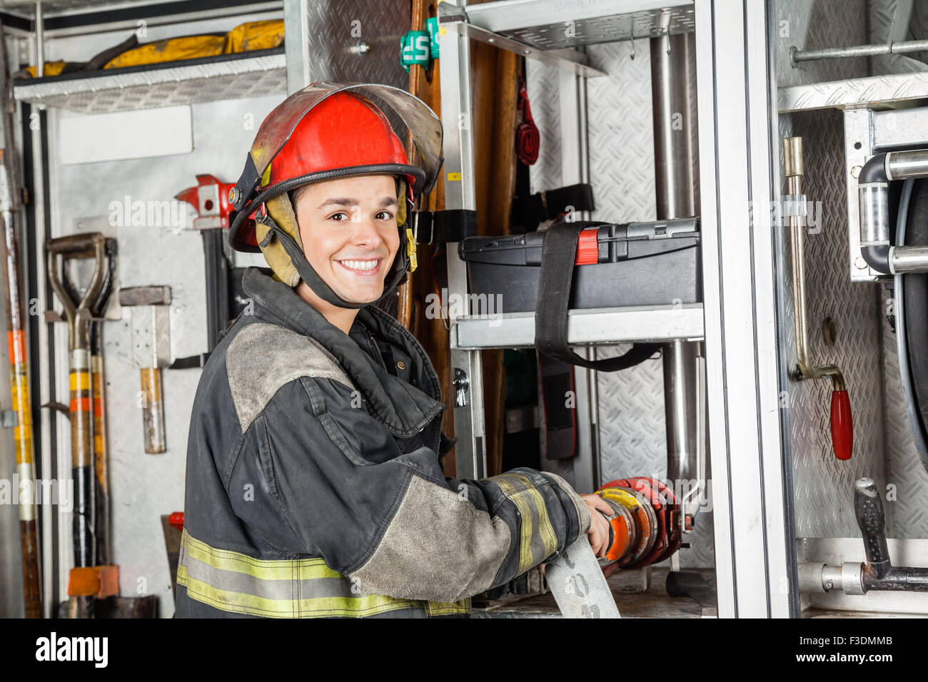 Happy Firefighter Fixing Water Hose In Truck Stock Photo - Alamy