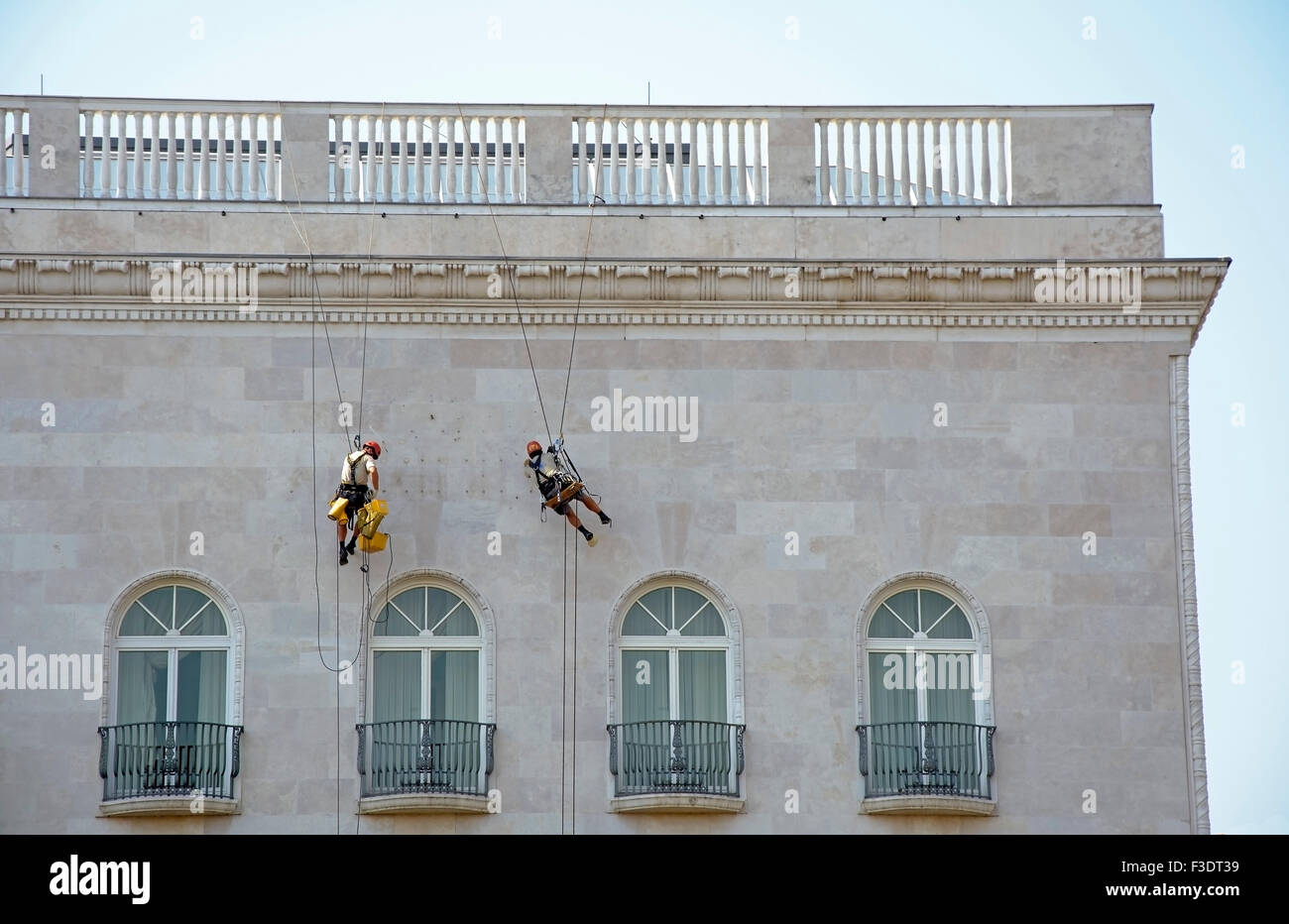 two people work on the wall of a tall building Stock Photo - Alamy