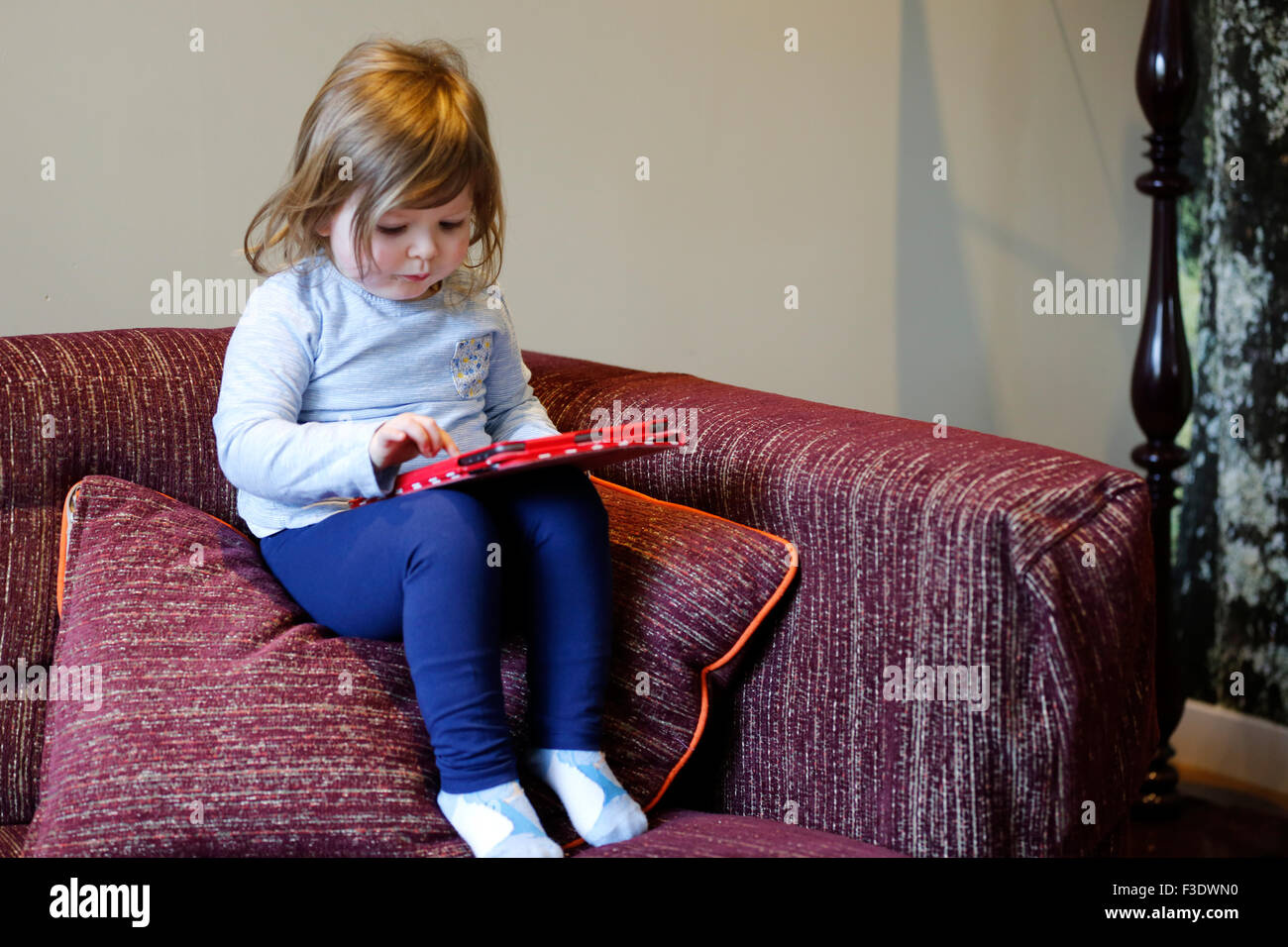 A young child at home using an ipad or tablet. Despite her age shes ...