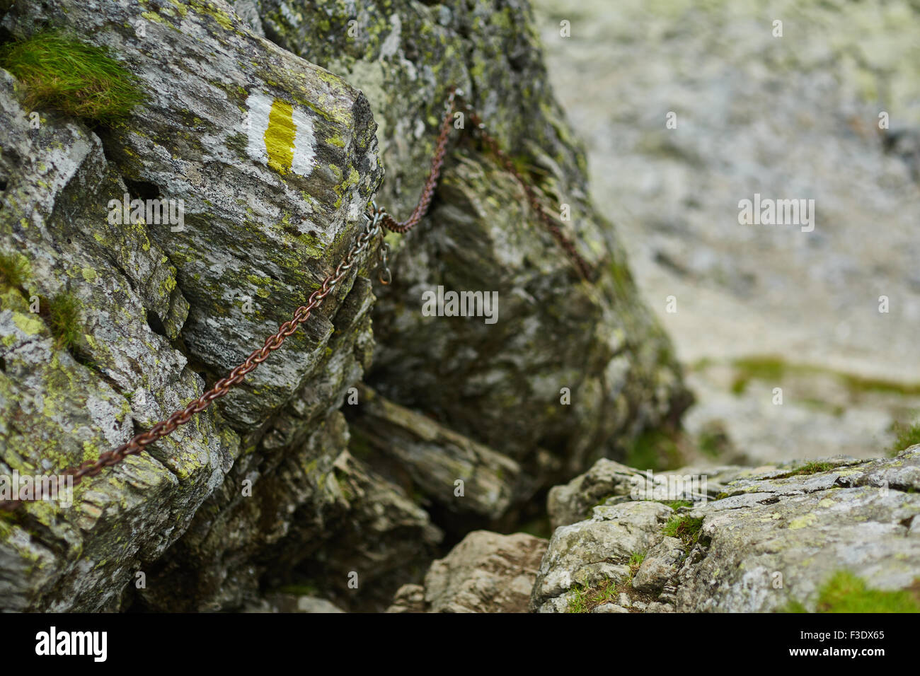 Marked trail with safety chains through rocky mountains, selective ...