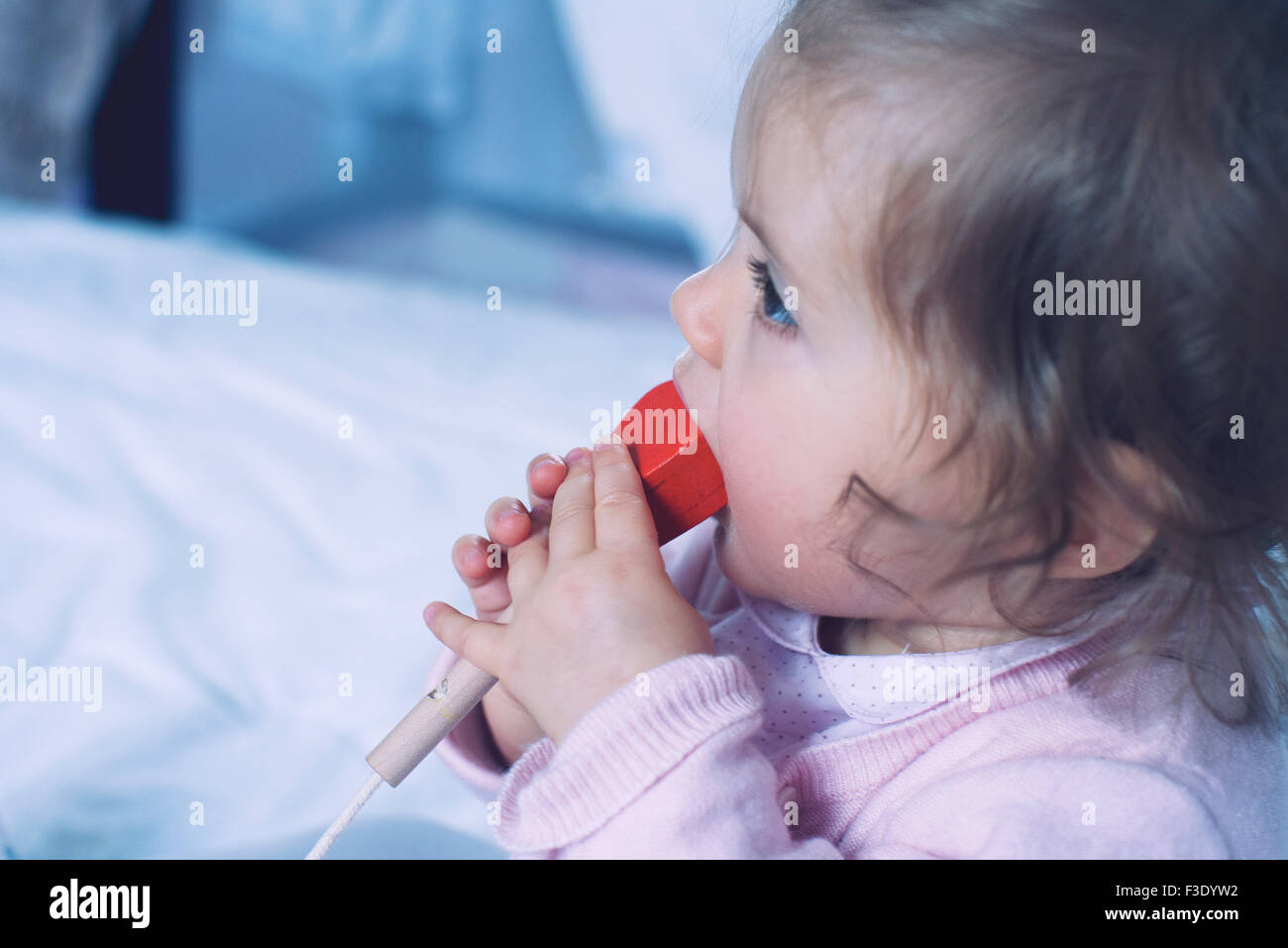 Baby girl chewing on toy Stock Photo - Alamy