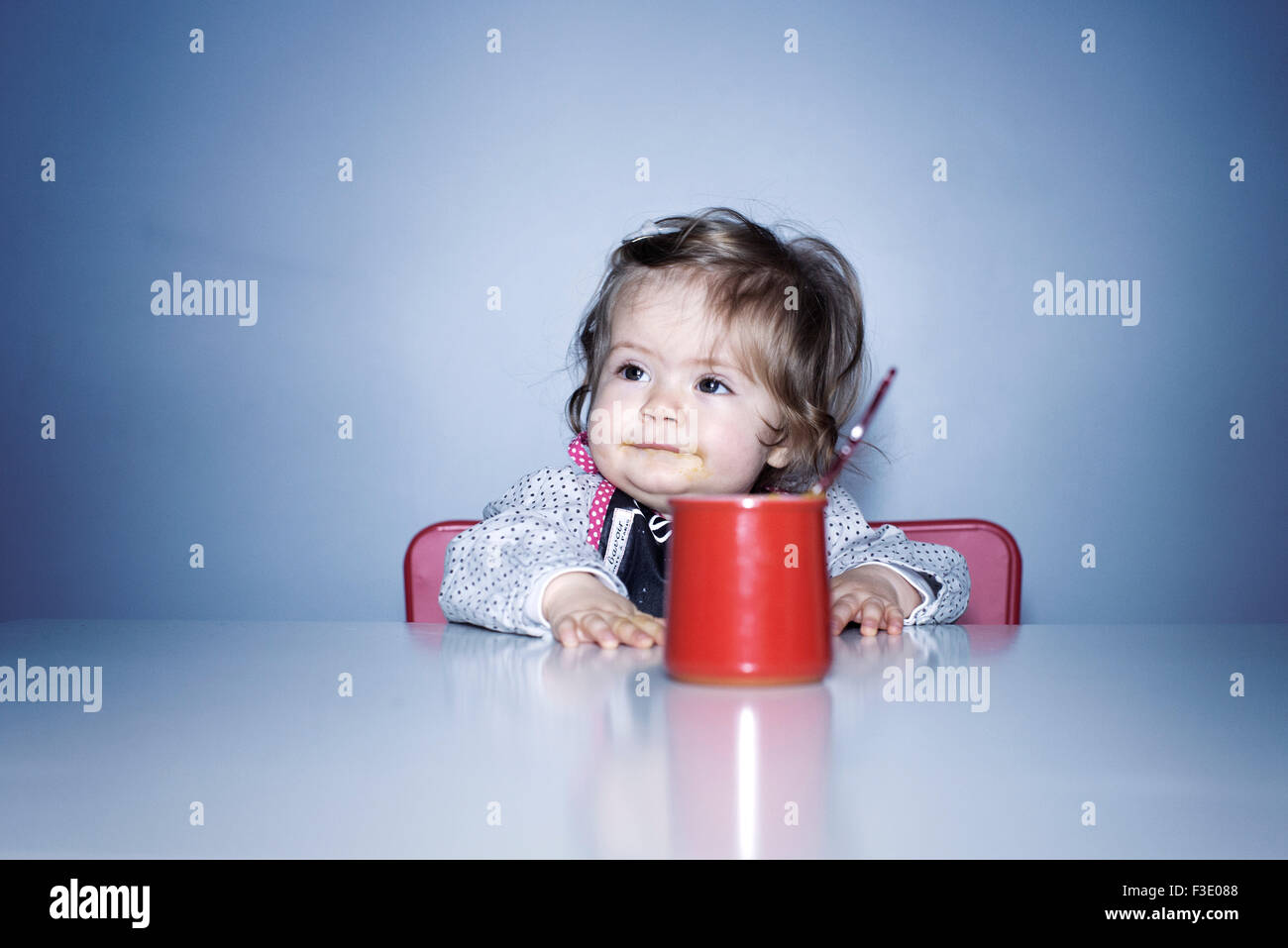 Baby girl sitting at table, portrait Stock Photo - Alamy
