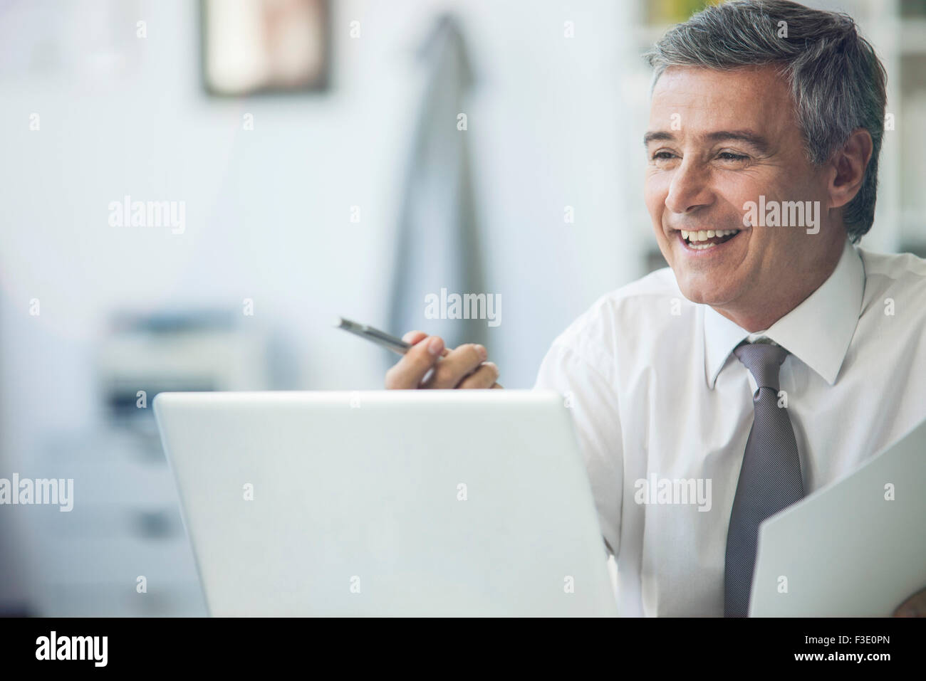 Mature businessman working in office, laughing Stock Photo - Alamy