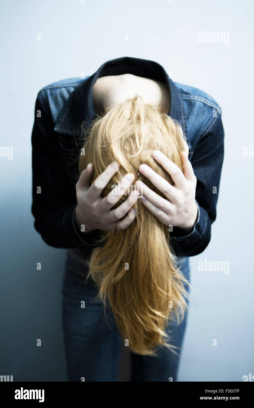 Woman leaning forward holding head Stock Photo - Alamy