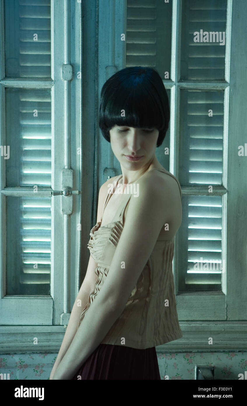 Woman standing by window, looking down Stock Photo - Alamy