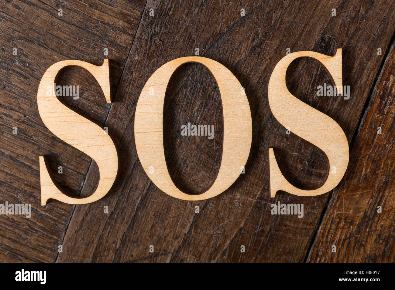 Wooden letters forming word SOS written on old vintage wooden plates ...