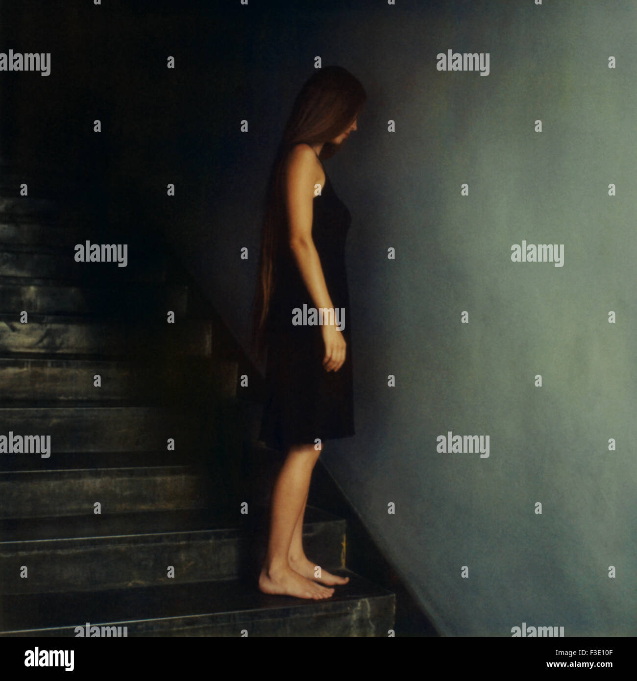 Woman standing on stairs, facing wall Stock Photo - Alamy