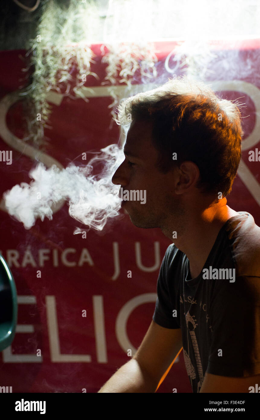 A young red haired man smokes a cigar while socializing in a bar on the ...