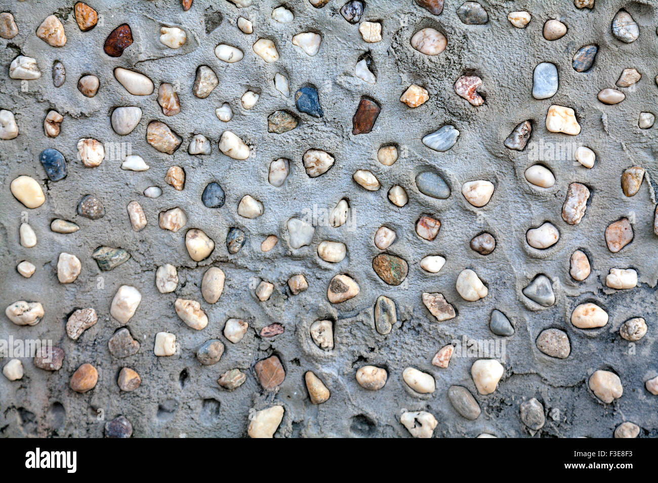 Small pebbles set in concrete wall texture Stock Photo - Alamy