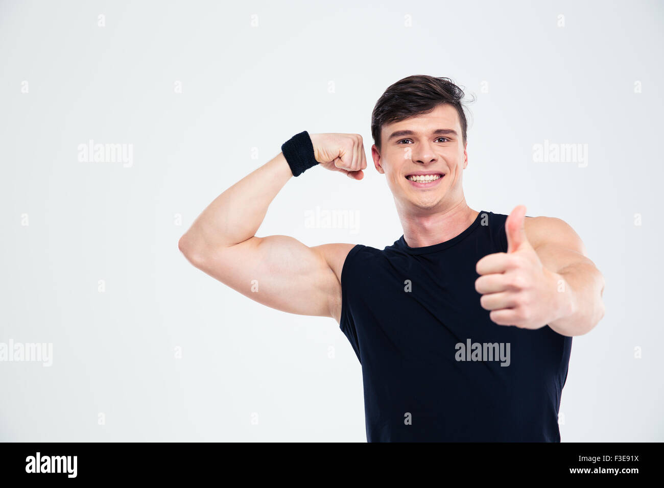Portrait of a smiling fitness man showing his biceps and thumb up ...