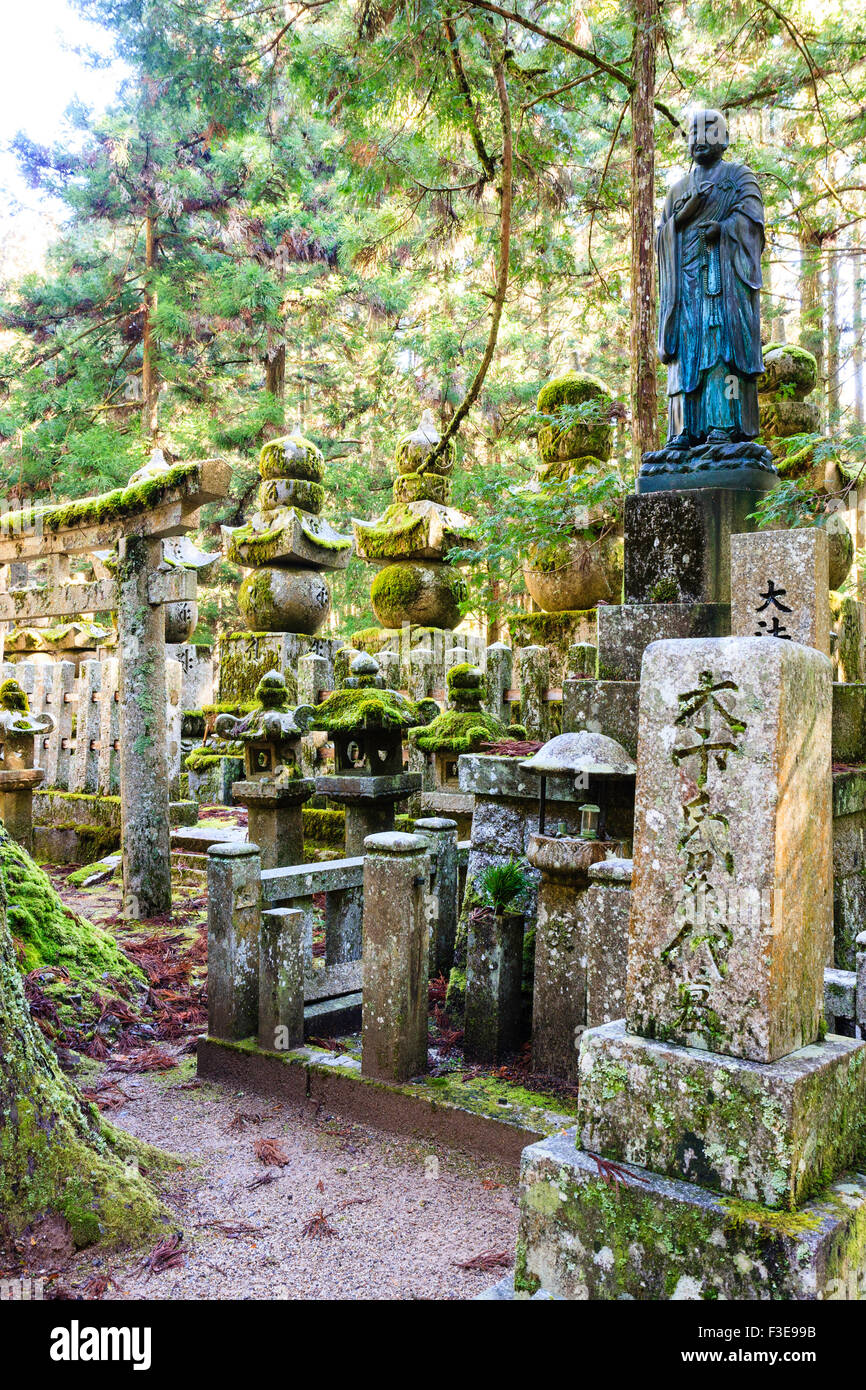 Japan, Koyasan cemetery, Okunoin. Statue of priest on large tombstone ...