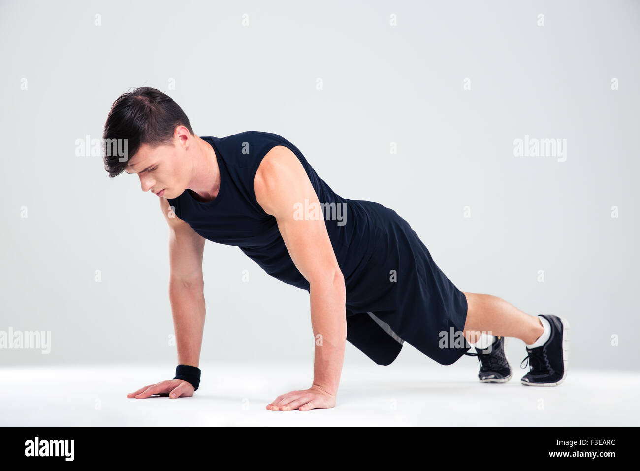 Portrait of a fitness man doing push ups isolated on a white background ...