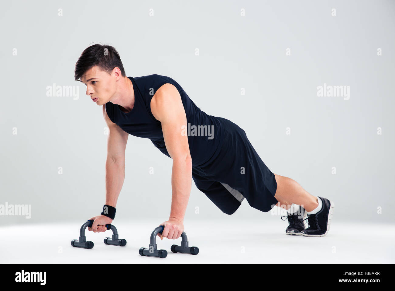 Portrait of a fitness man doing push ups isolated on a white background ...