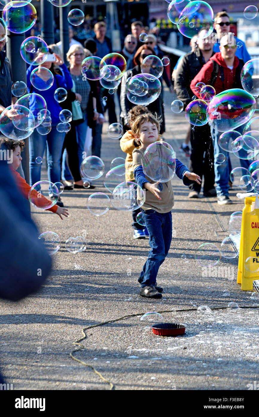 London, England, UK. Young boy chasing bubbles made by a street ...