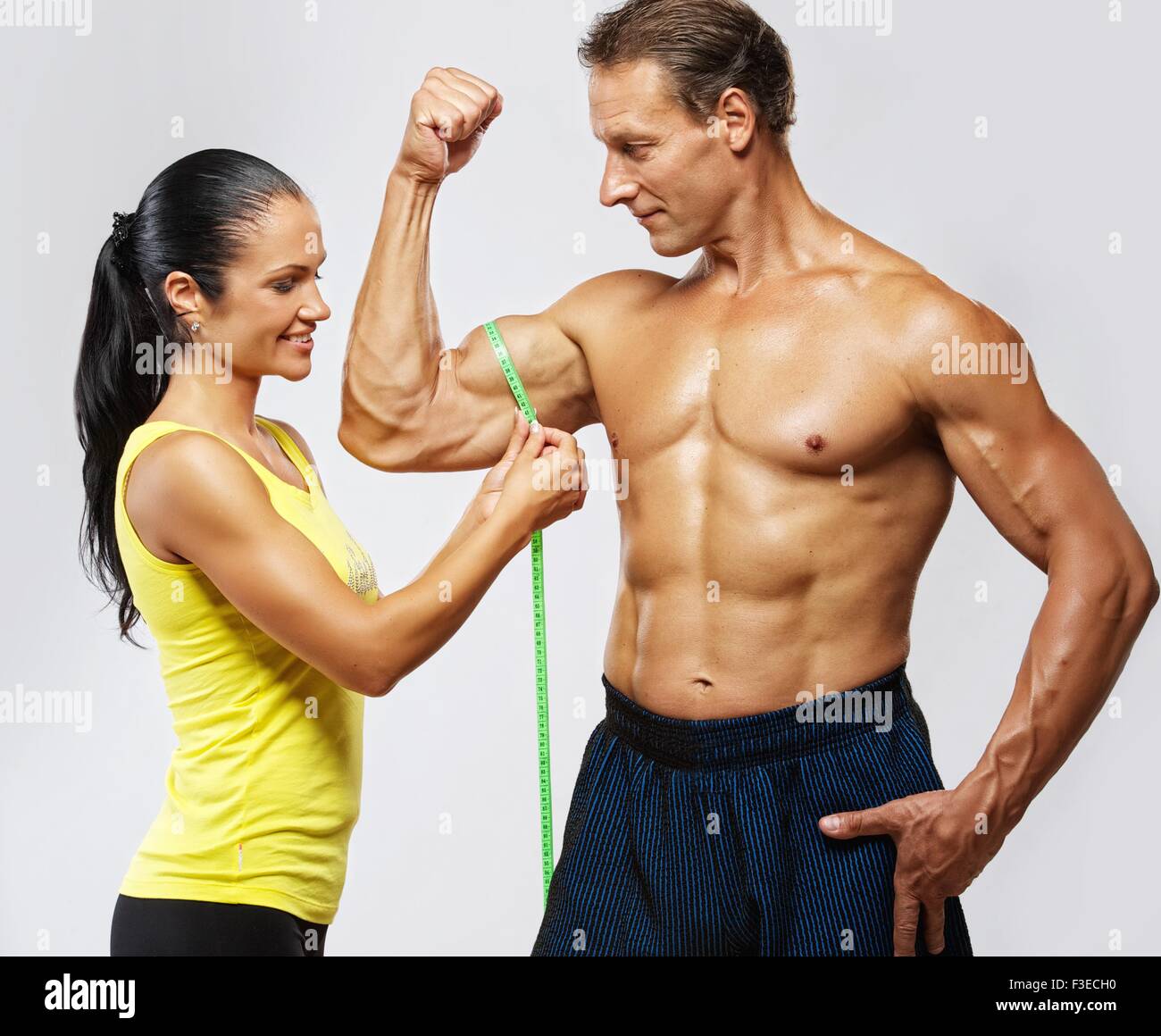 Woman measuring athletic's man biceps Stock Photo - Alamy