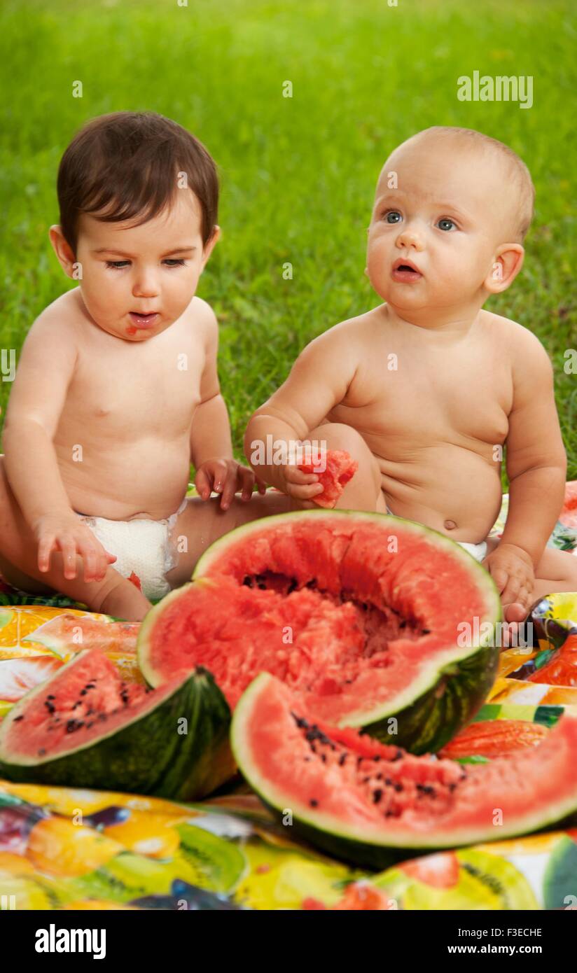 Two babies eating watermelon outdoors Stock Photo - Alamy