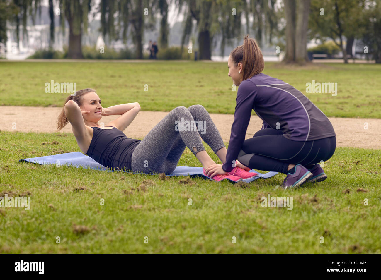 Serious Athletic Woman looking at her friend While Doing Curl Up ...