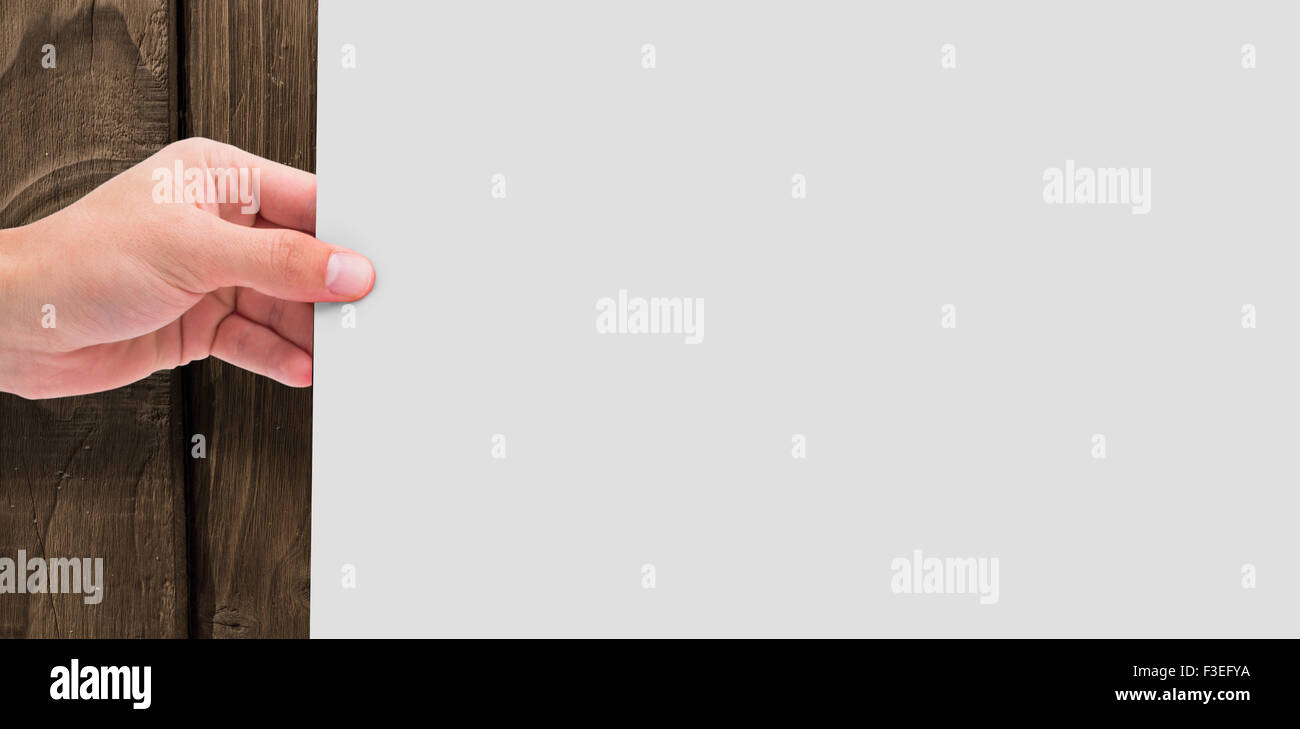 Hand holding paper against wooden wall Stock Photo - Alamy