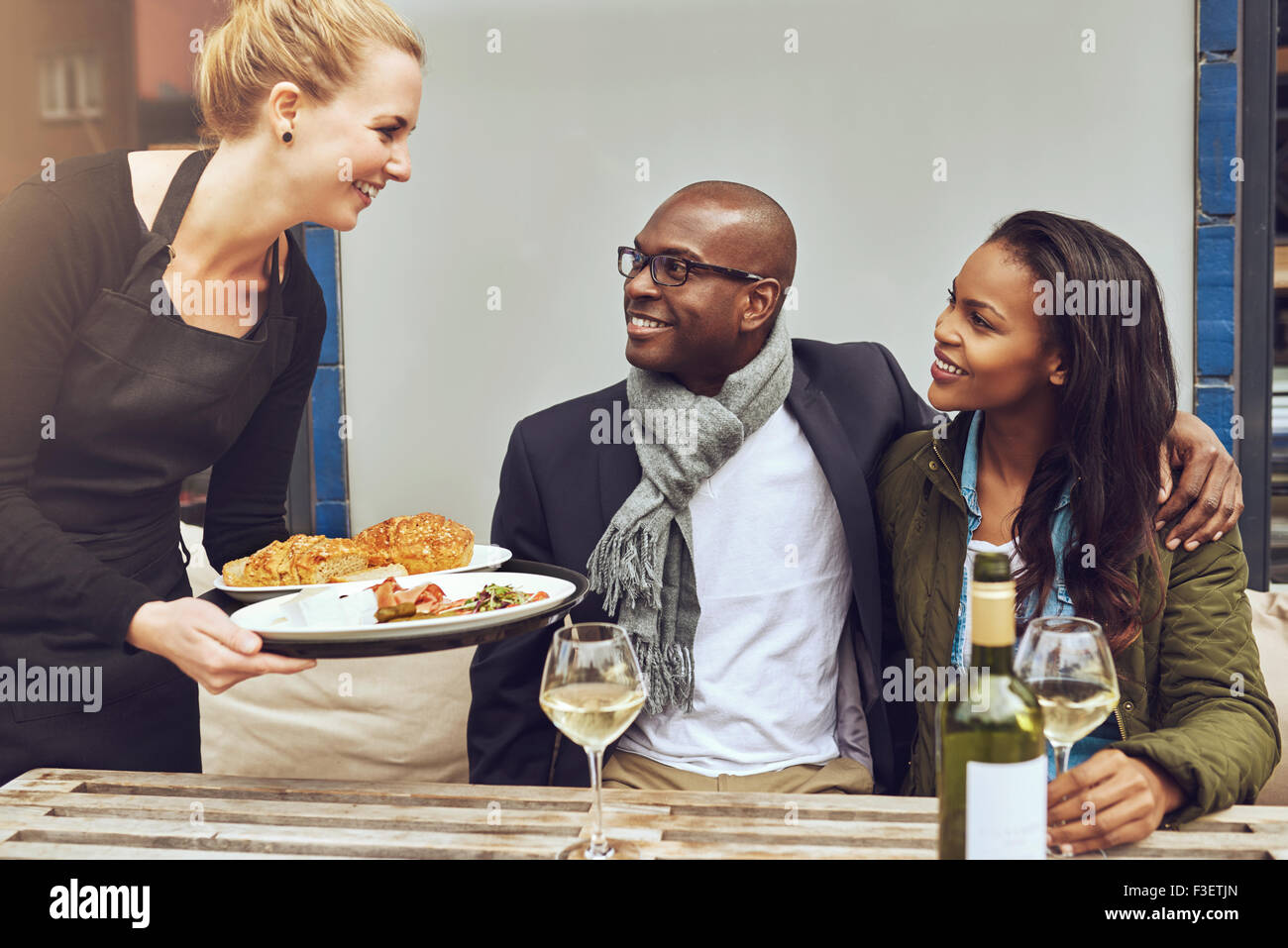 Smiling happy young Caucasian waitress serving a loving African ...