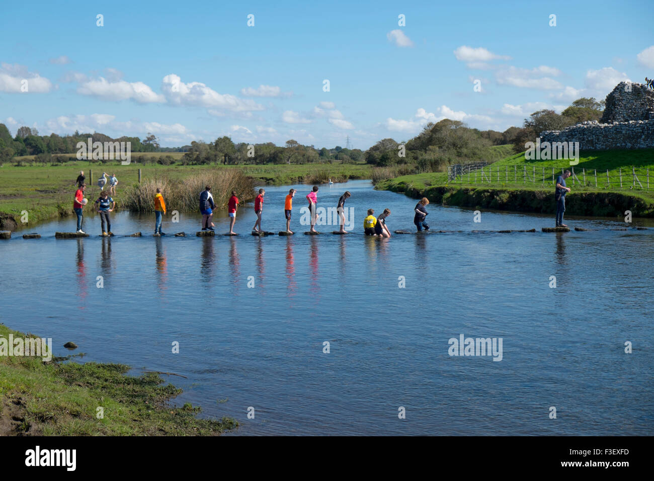 Children using stepping stones to cross the River Ogmore near Ogmore ...