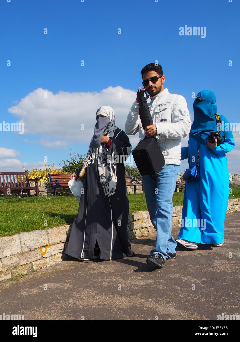 A muslim male in western clothes and two females wearing traditional ...