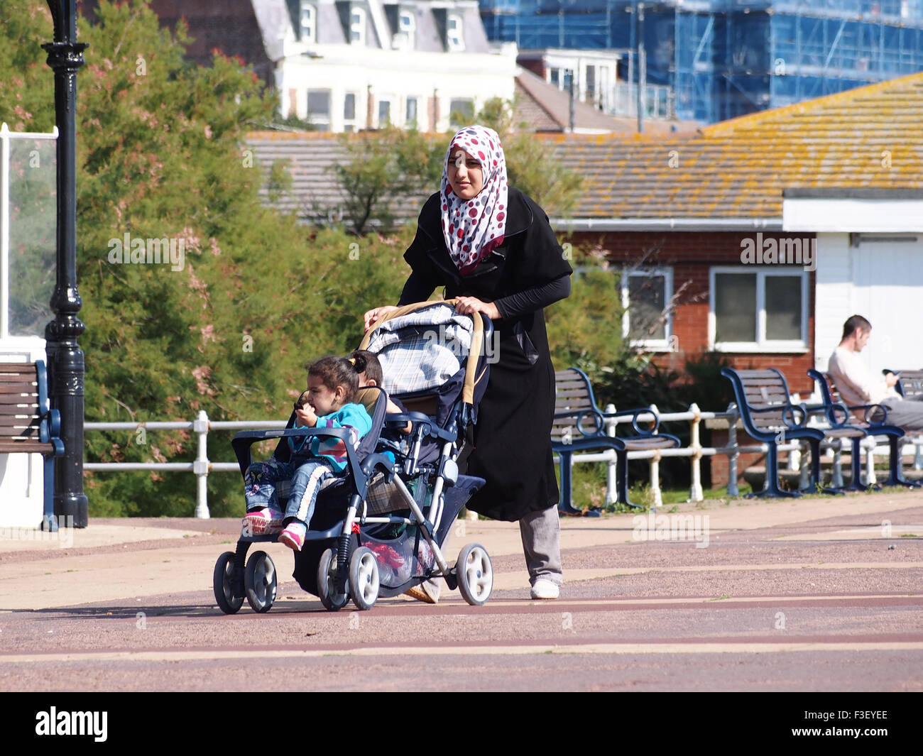 A muslim lady pushing a pushchair with two children inside it Stock ...
