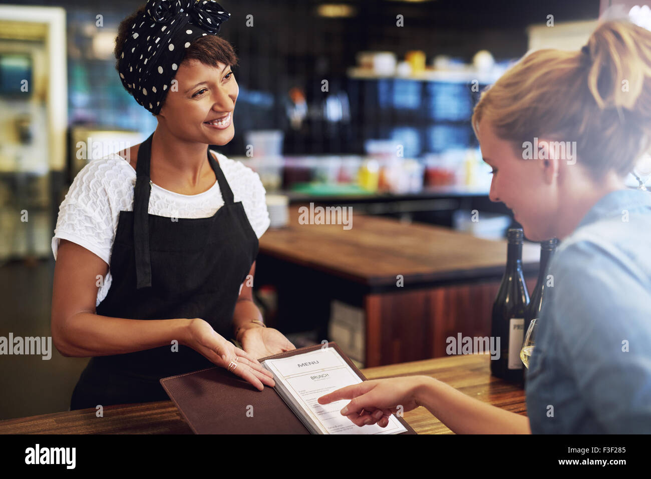Customer checking a wine menu in a pub being presented to her by an ...