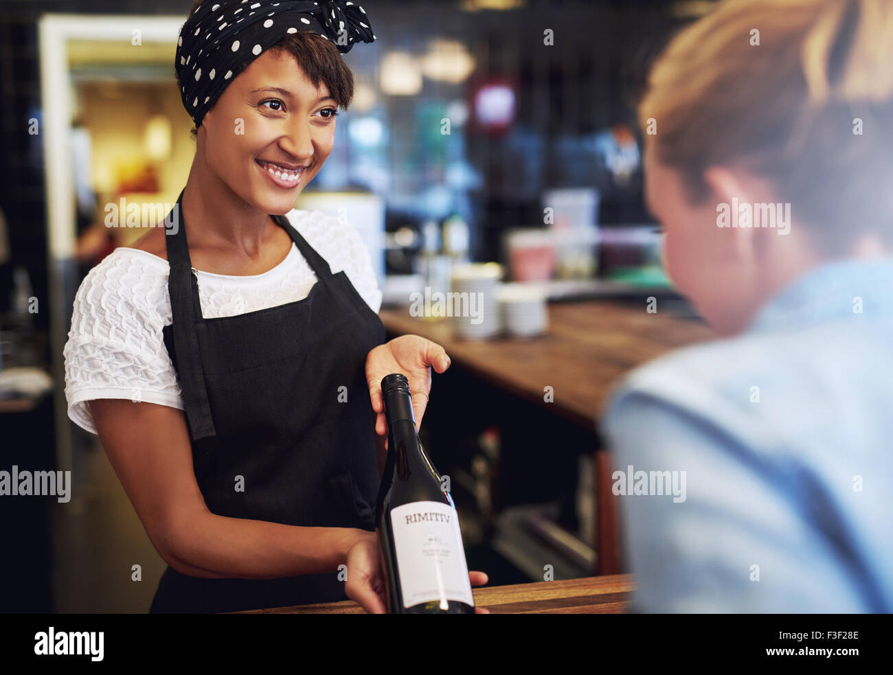 Smiling attractive young African American waitress or bartender showing ...
