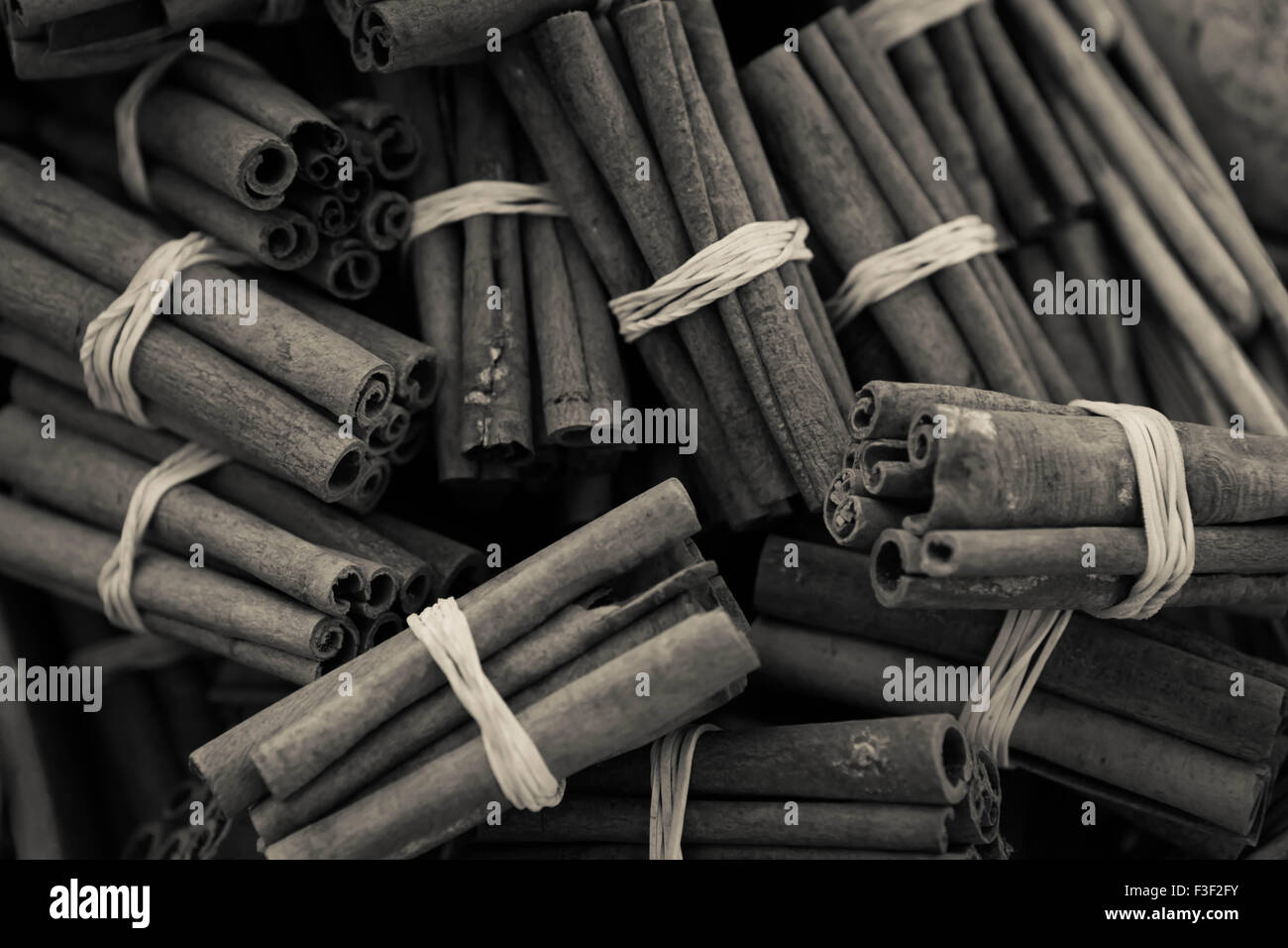 Pile of cinnamon sticks in bundles bound with twine in a wicker box ...