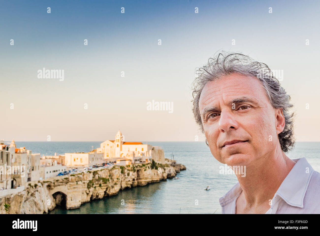charming middle-aged tanned man in white shirt in a seaside ancient ...