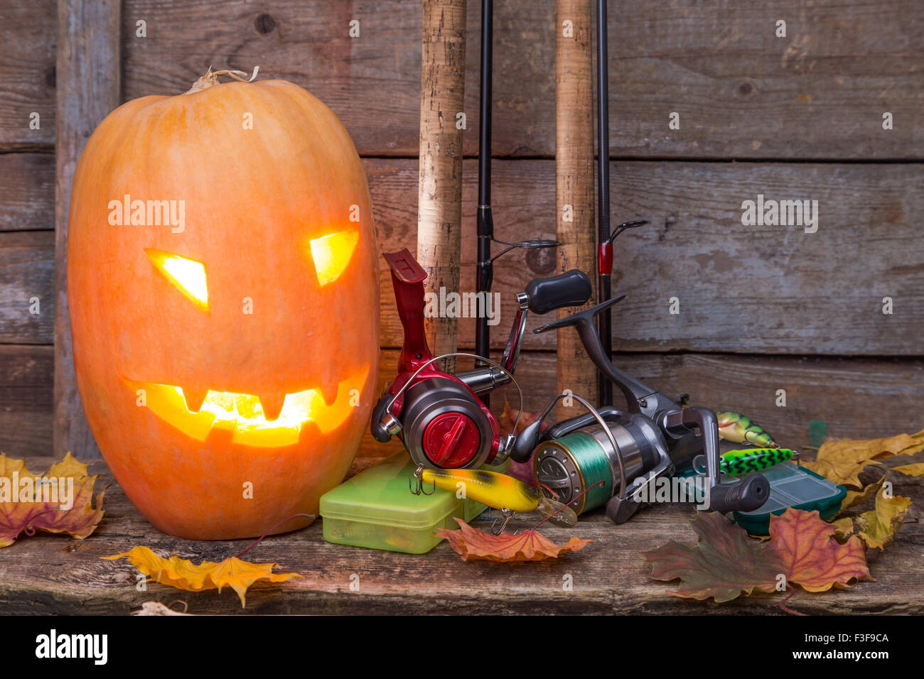 halloween pumpkin head with fishing tackles on wooden boards background ...