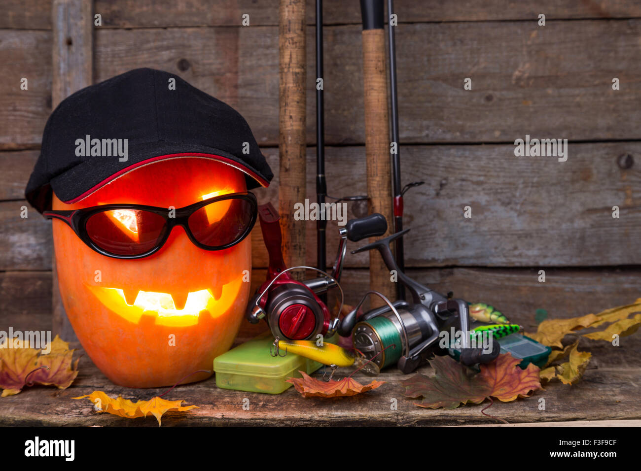 halloween pumpkin head in hat with fishing tackles on wooden boards ...