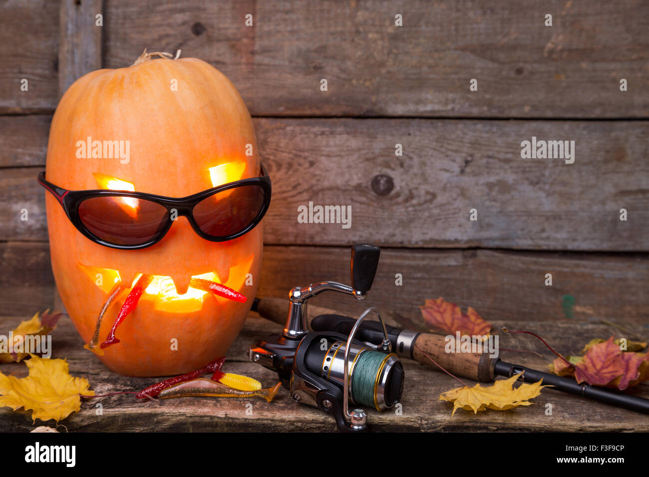 halloween pumpkin head in eyeglass with fishing tackles on wooden ...