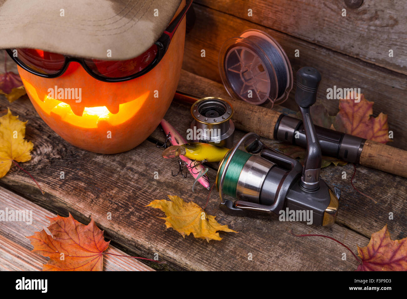 halloween pumpkin head in hat with fishing tackles on wooden boards ...