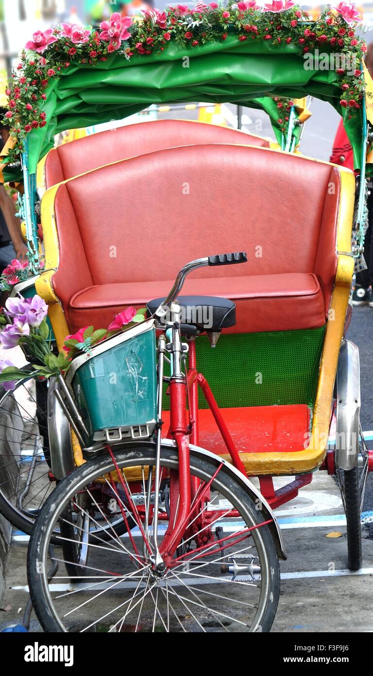Two traditional cycle rickshaws or pedicabs are parked by the side of ...