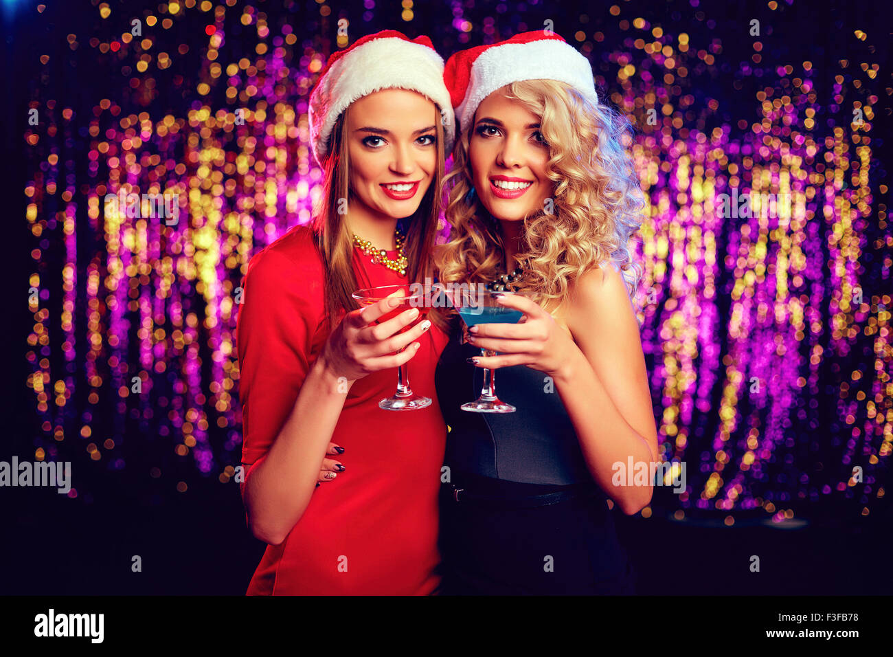 Pretty Santa girls with drinks looking at camera at party Stock Photo ...