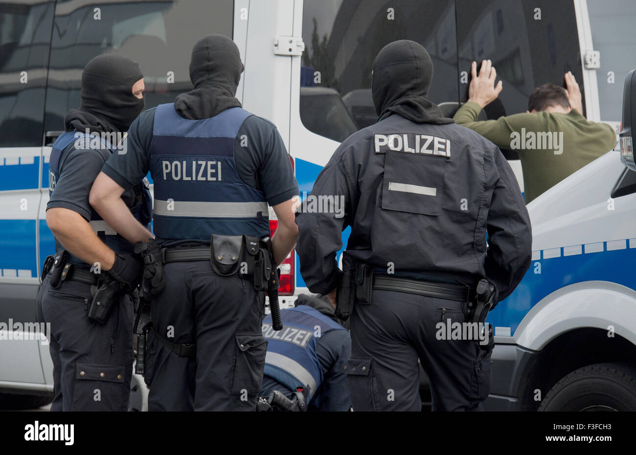 Masked police officers are in action and are searching a man at the ...