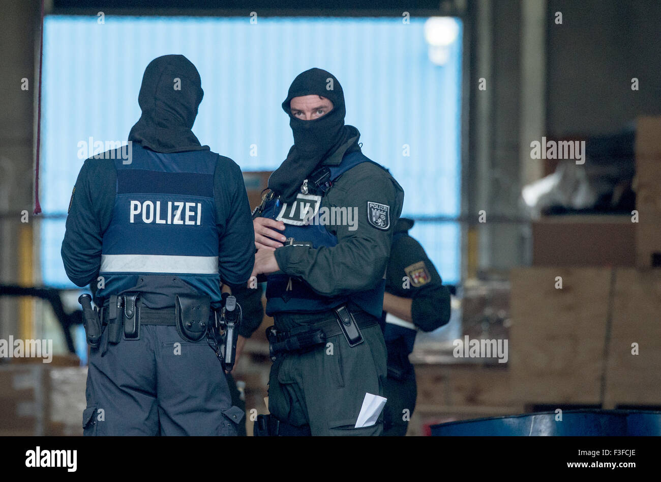 Masked police officers are in action and searching a warehouse at the ...