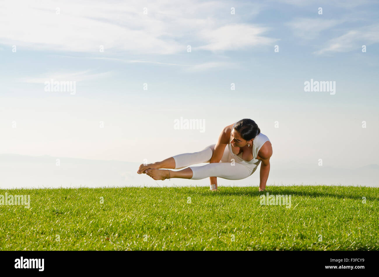 Young woman practising Hatha-Yoga outdoor, showing the pose kakasana ...