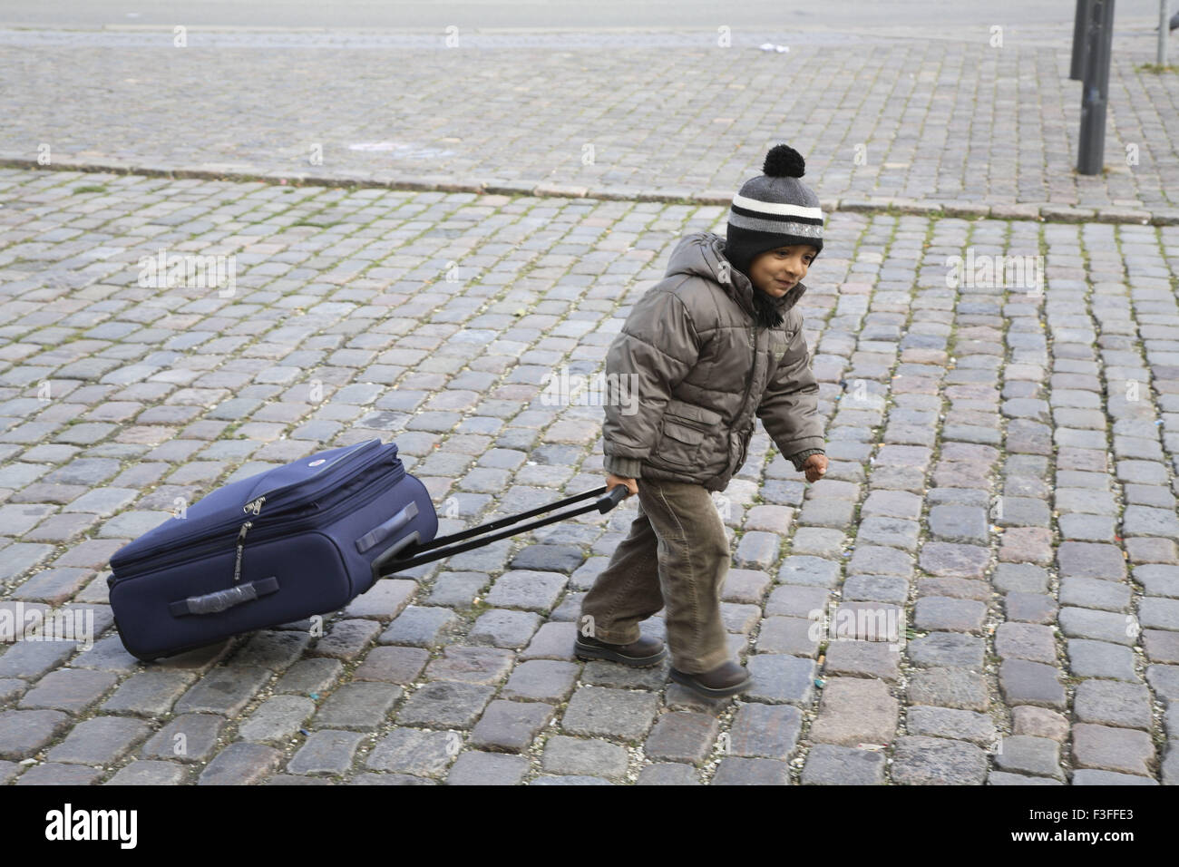 Small four years old boy pulling dark blue coloured luggage trolley bag ...