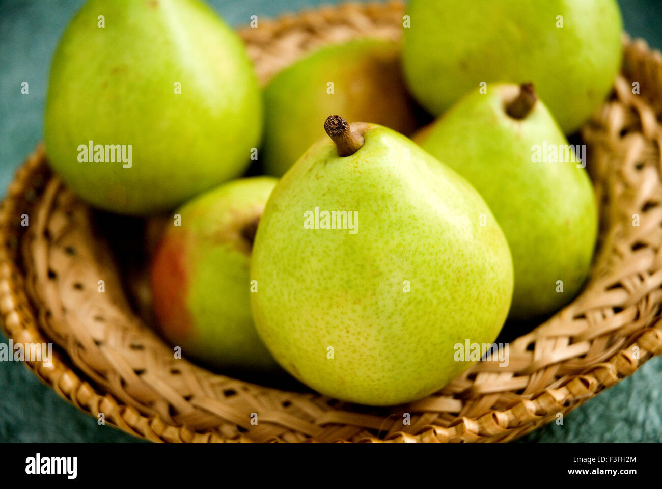 Pear fruit six in cane basket on blue background in studio Stock Photo ...